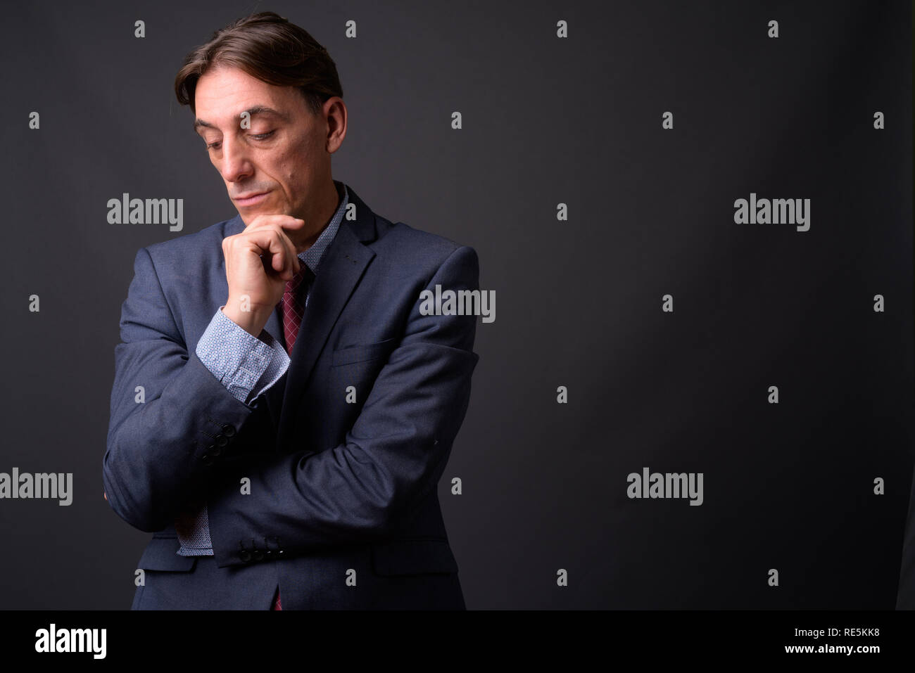Mature handsome Italian businessman thinking against gray background ...