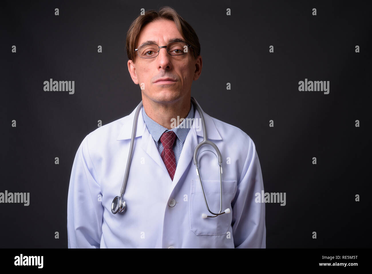 Mature handsome Italian man doctor against gray background Stock Photo ...