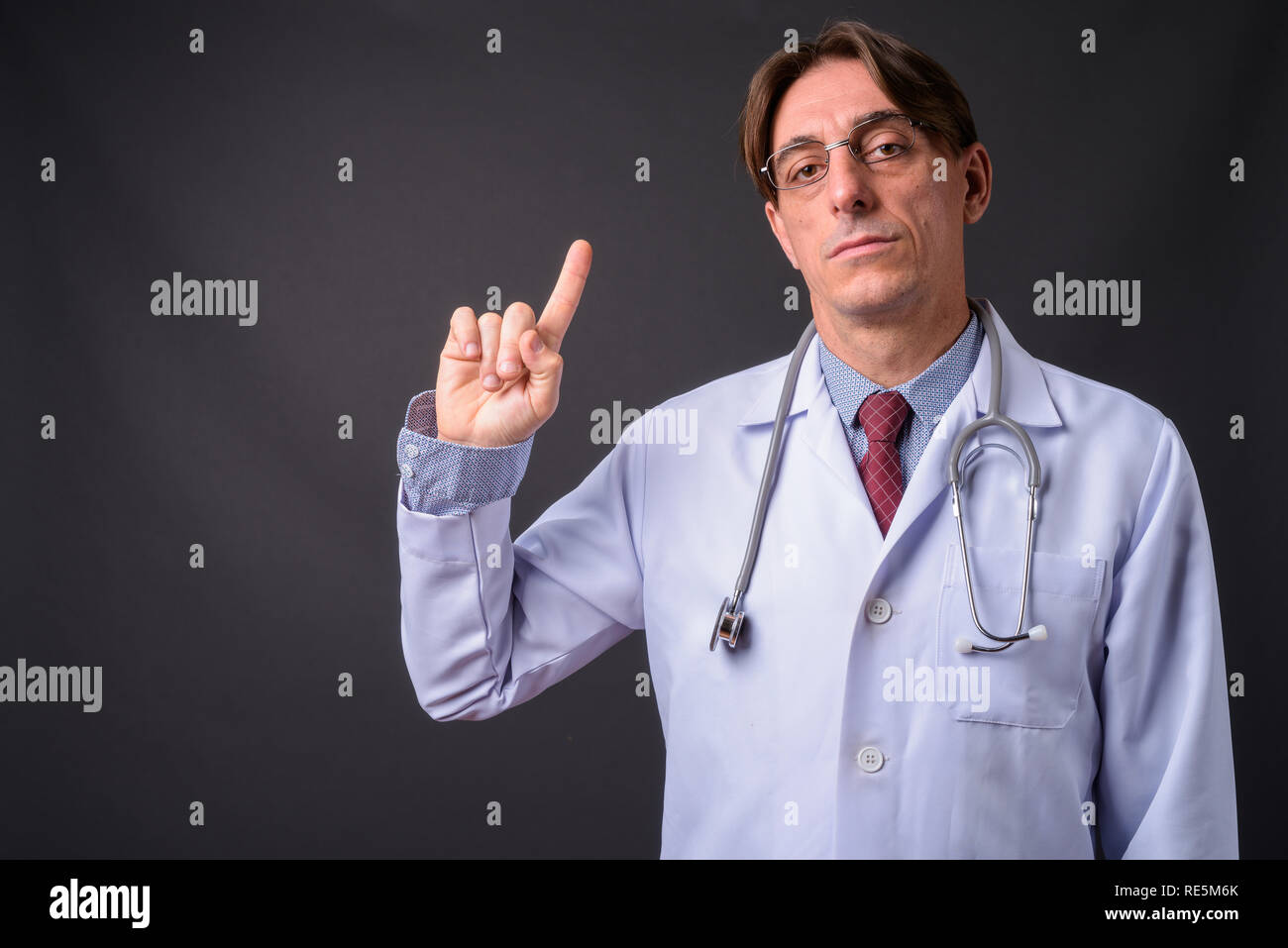 Mature handsome Italian man doctor pointing finger up Stock Photo - Alamy