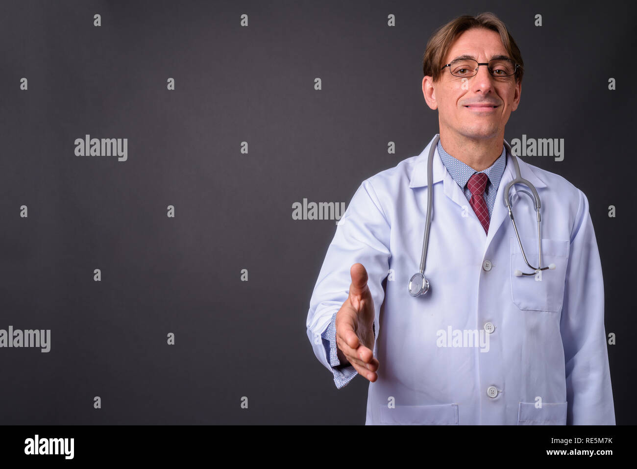Mature handsome Italian man doctor giving handshake Stock Photo - Alamy