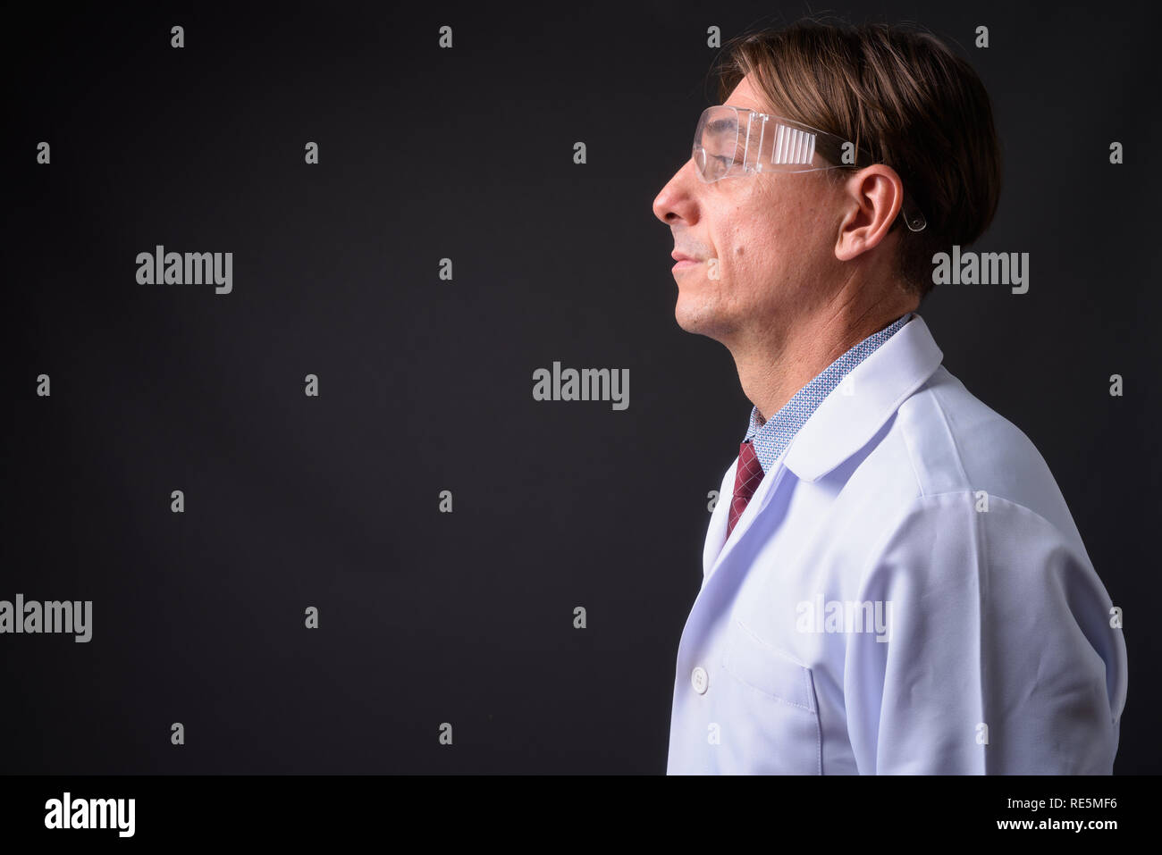 Profile view of mature handsome Italian man doctor wearing protective ...
