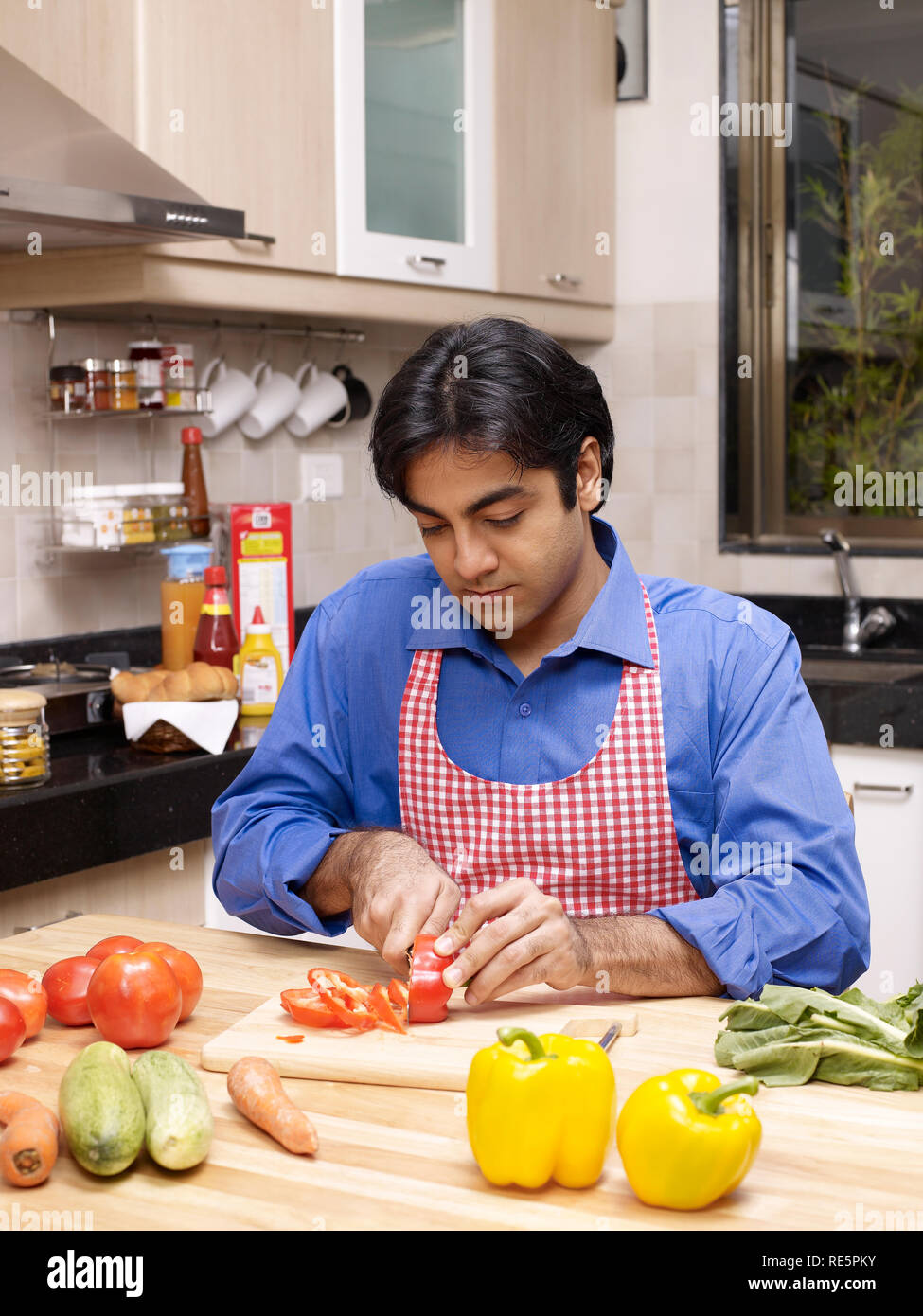 YOUNG MAN CUTTING VEGETABLES IN THE KITCHEN Stock Photo - Alamy