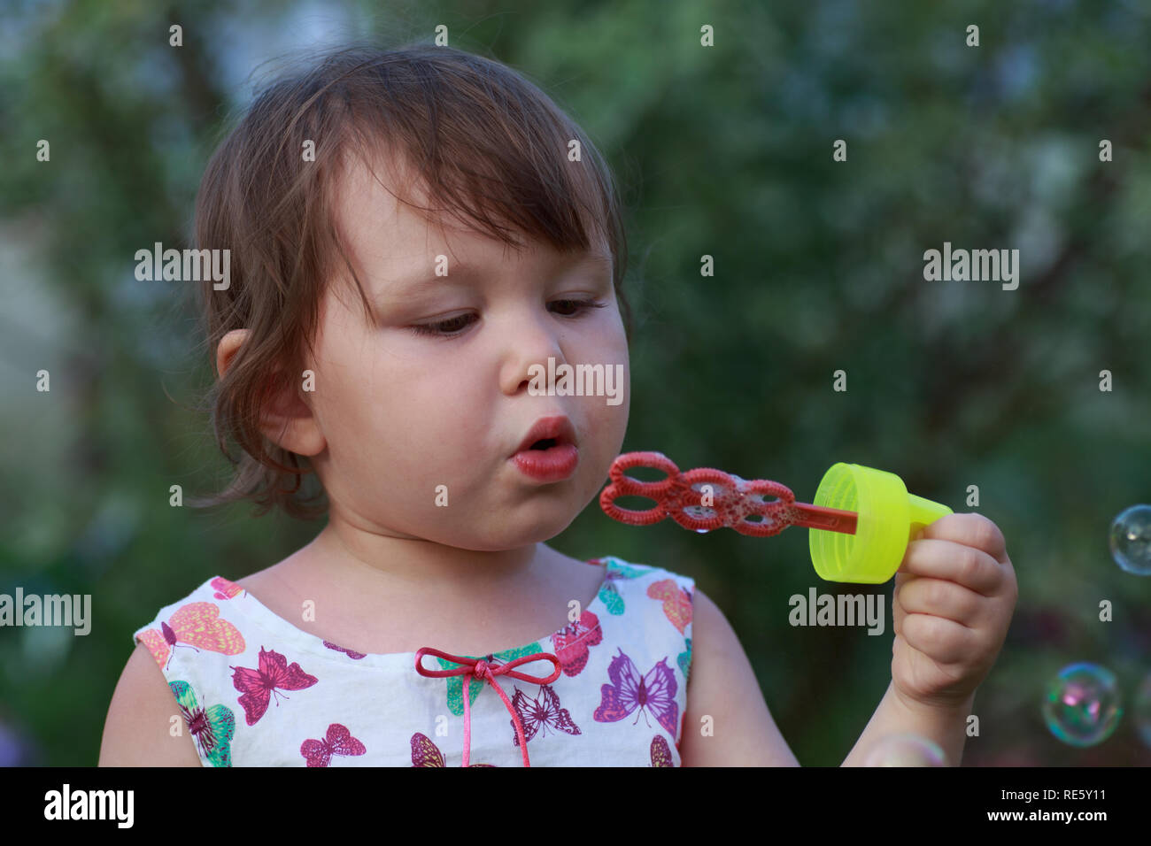 Cute little girl is blowing a soap bubbles Stock Photo - Alamy