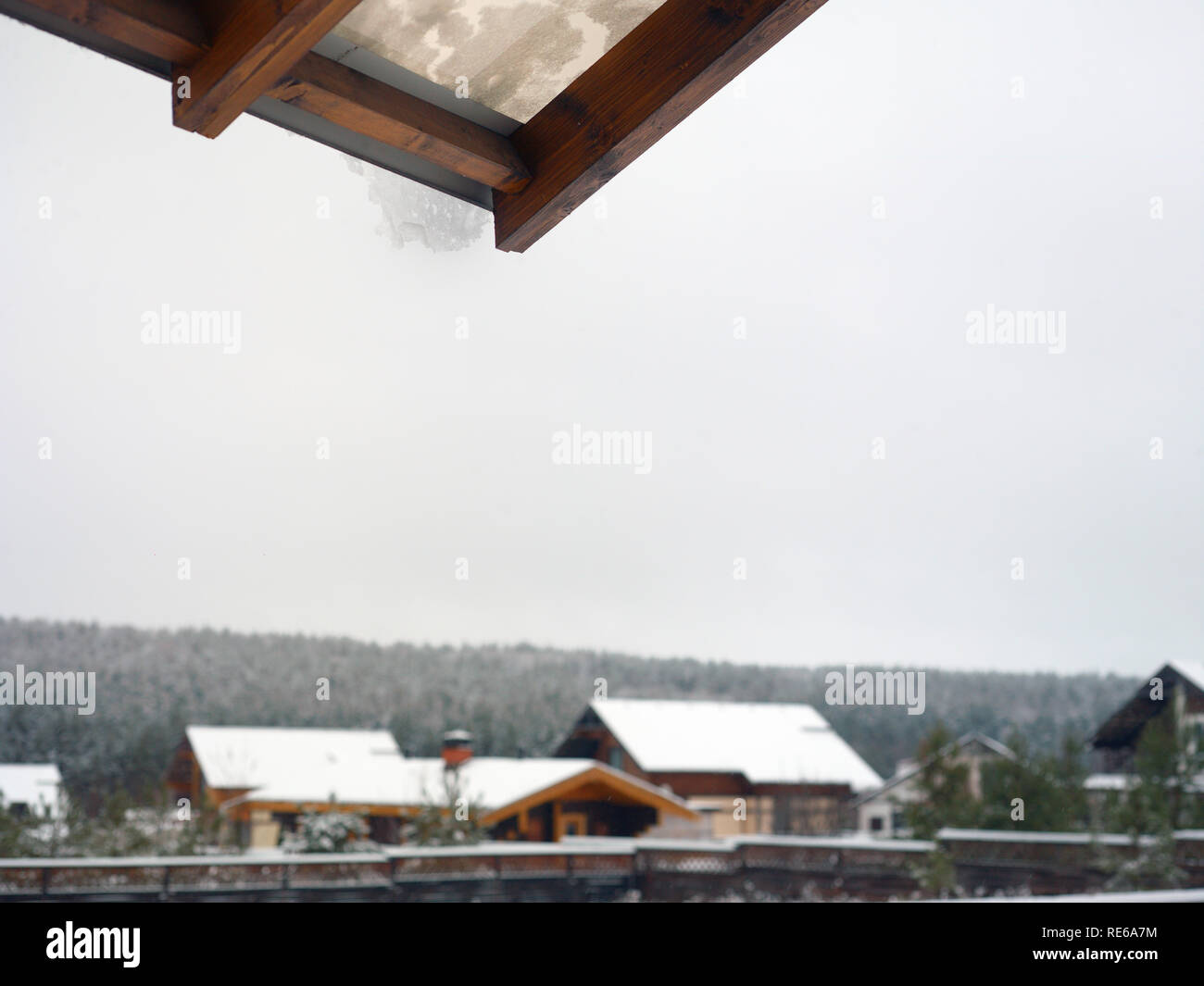 A house roff with hanging snow and against the winter sky, a village in ...
