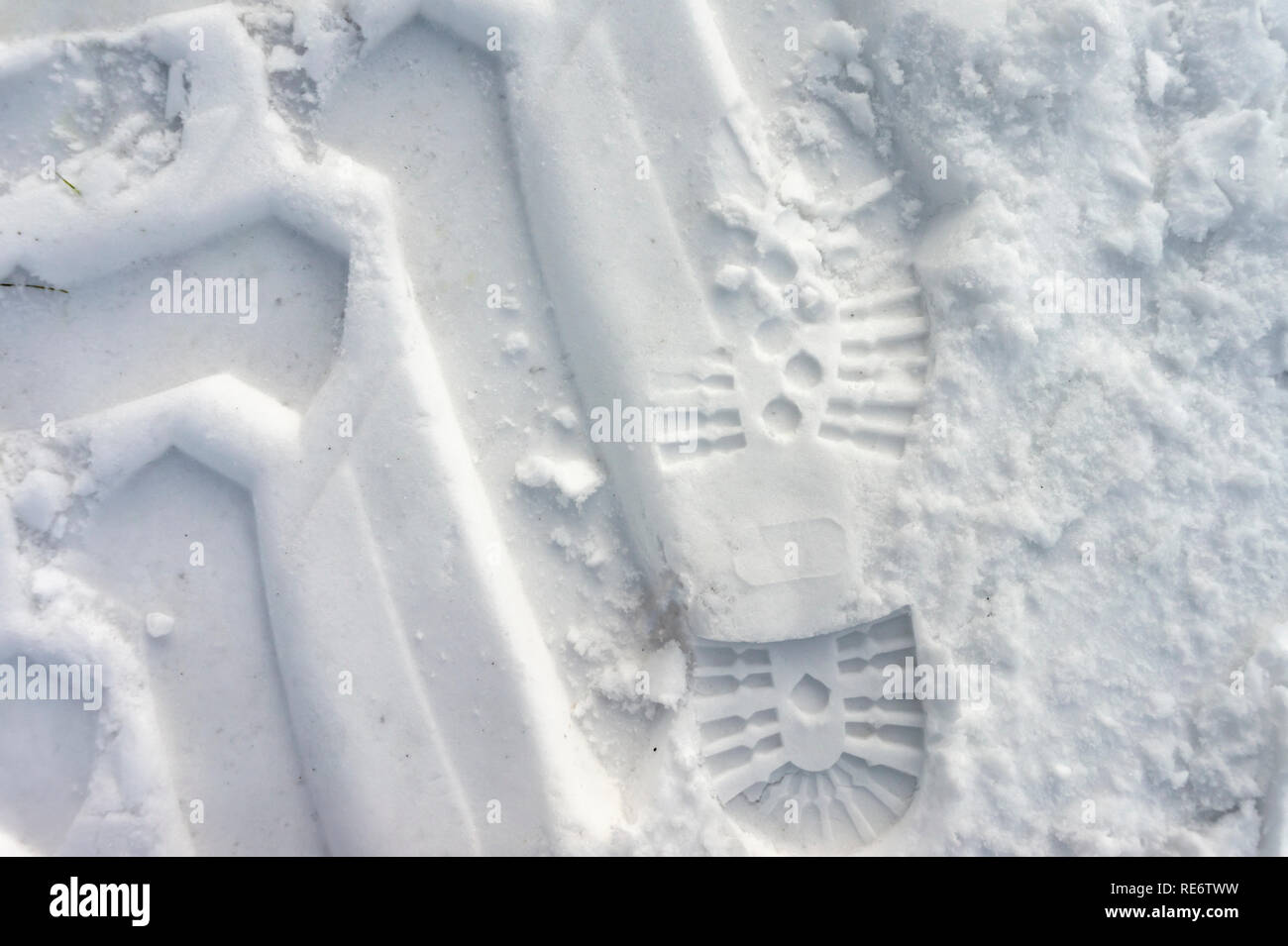Heavy duty vehicle tracks in fresh white winter snow with a boot print ...