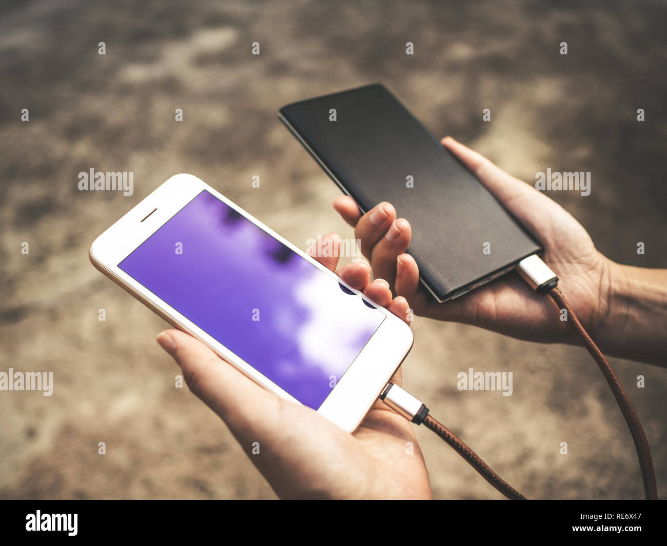 Human hands holding white smartphone charging battery from external ...