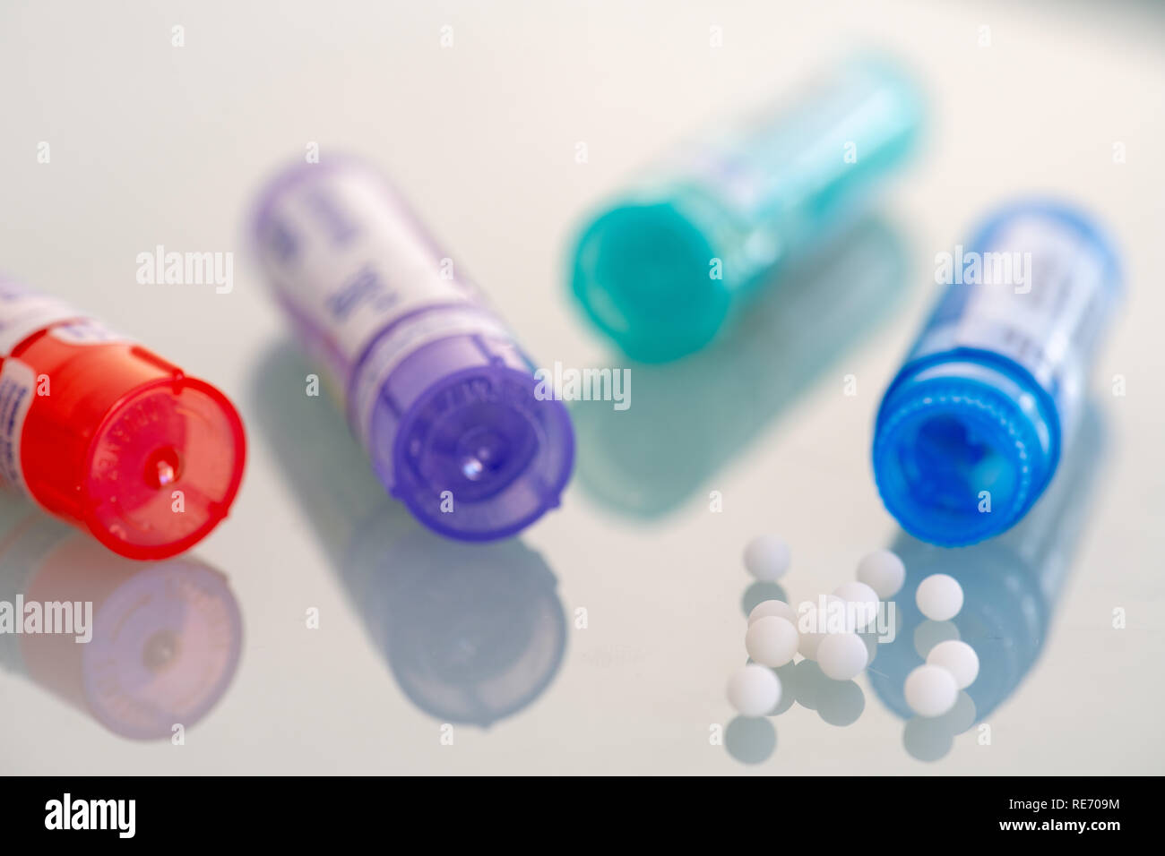Homeopathic globules scattered around with their colored containers in ...
