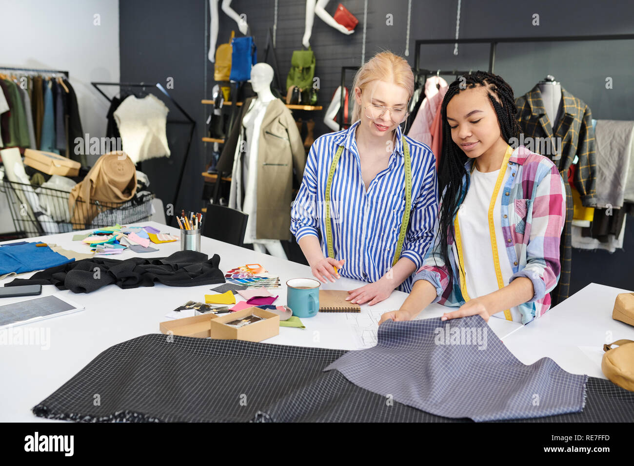 Two fashion designers looking at two different pieces of fabric and ...