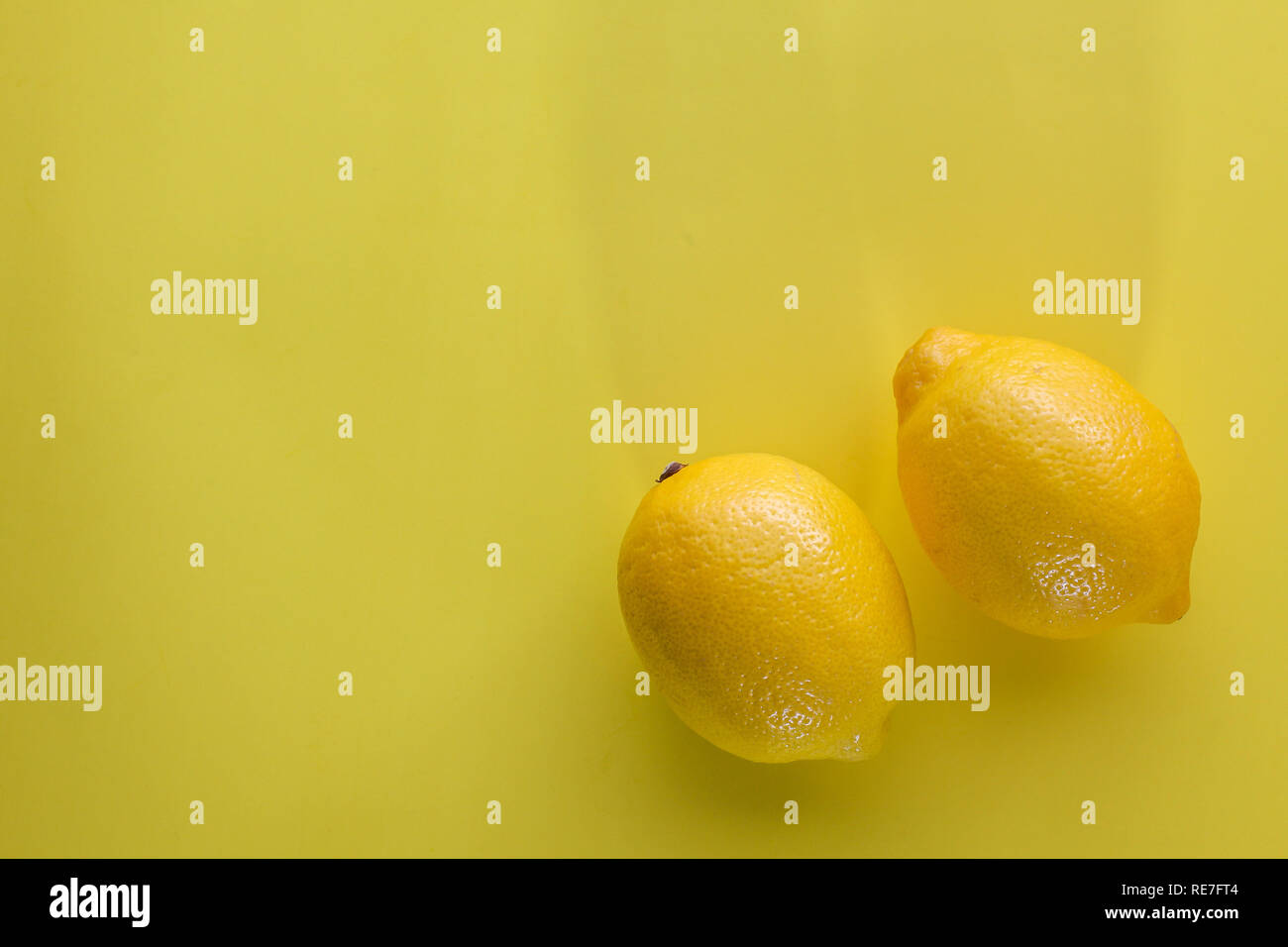 Two lemons on yellow background table top view Stock Photo - Alamy