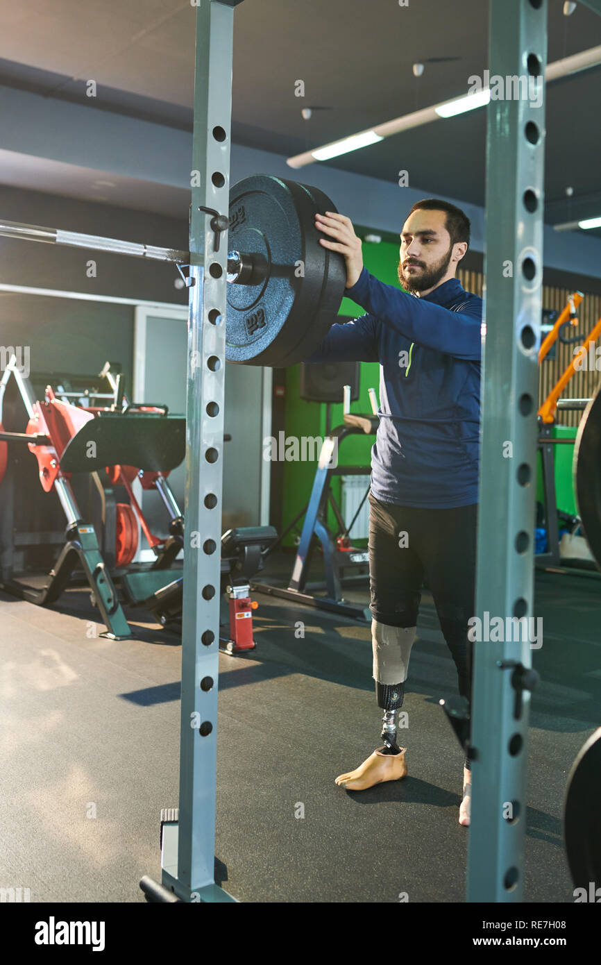 Young sportsman with amputee leg is going to training with barbell in ...