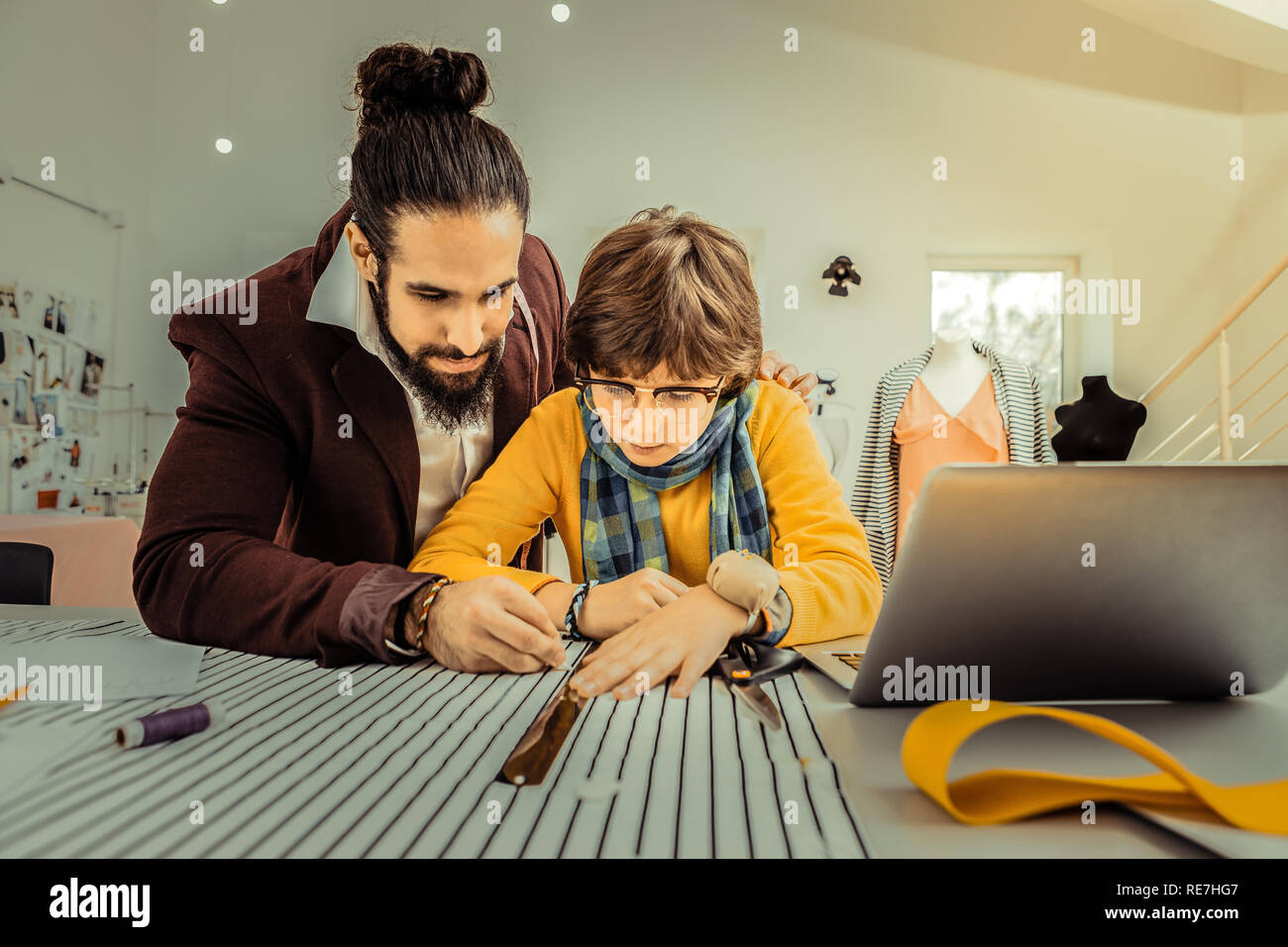 Father working as fashion designer showing his workplace to son Stock ...