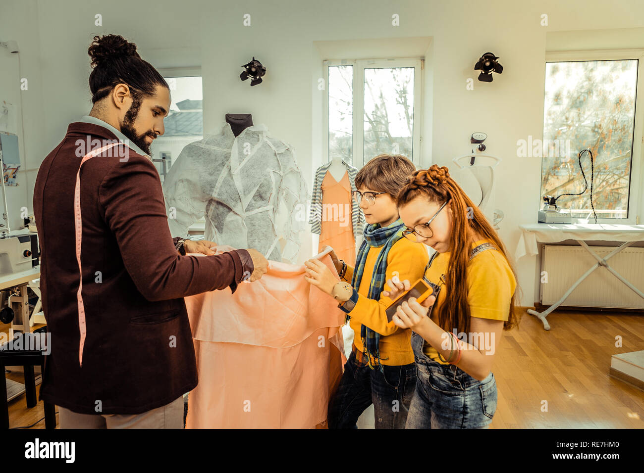 Son helping his father holding light pink fabric while designing ...