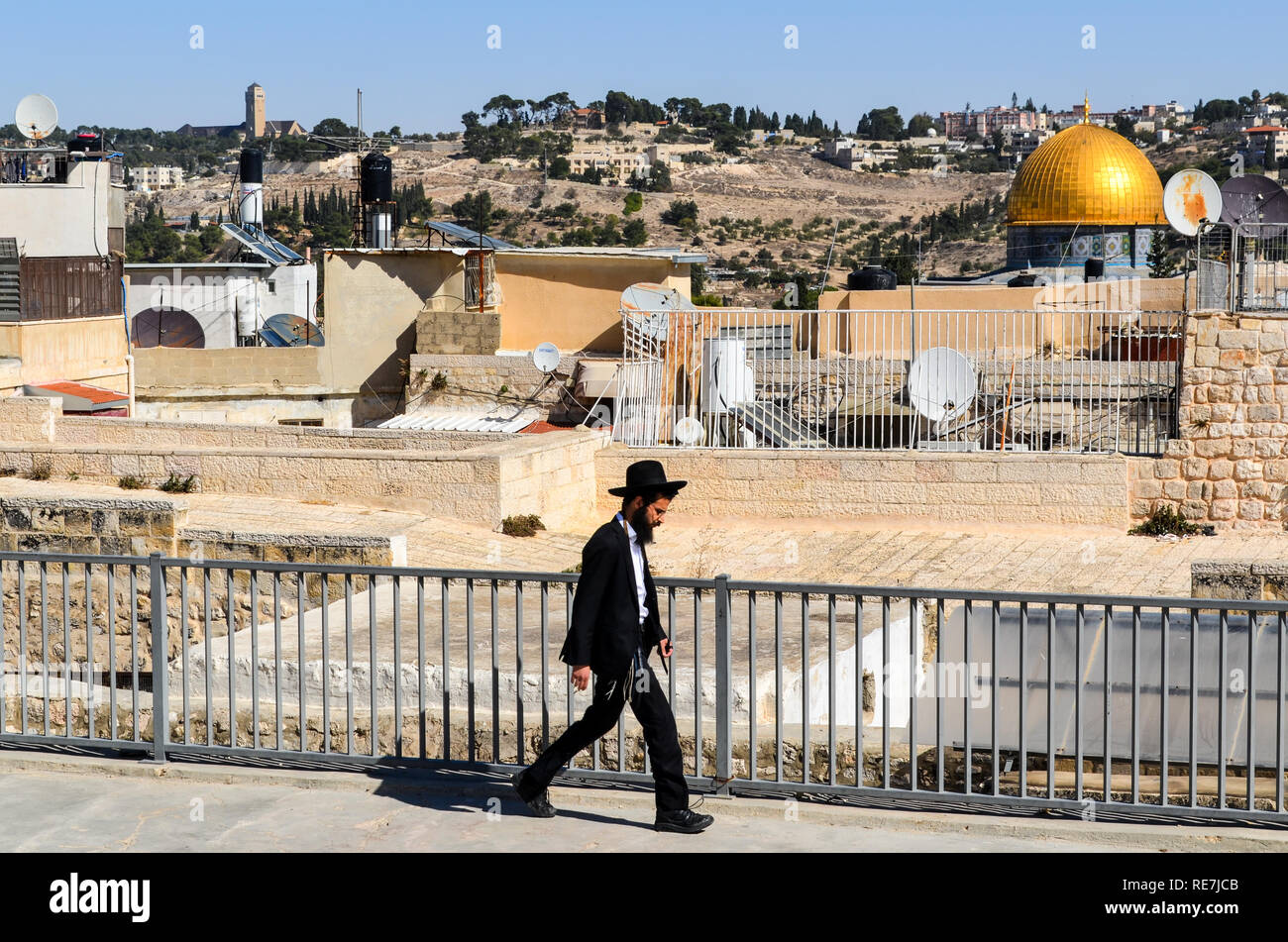 Orthodox Jewish man walking on the rooftops of Jerusalem, with Temple ...