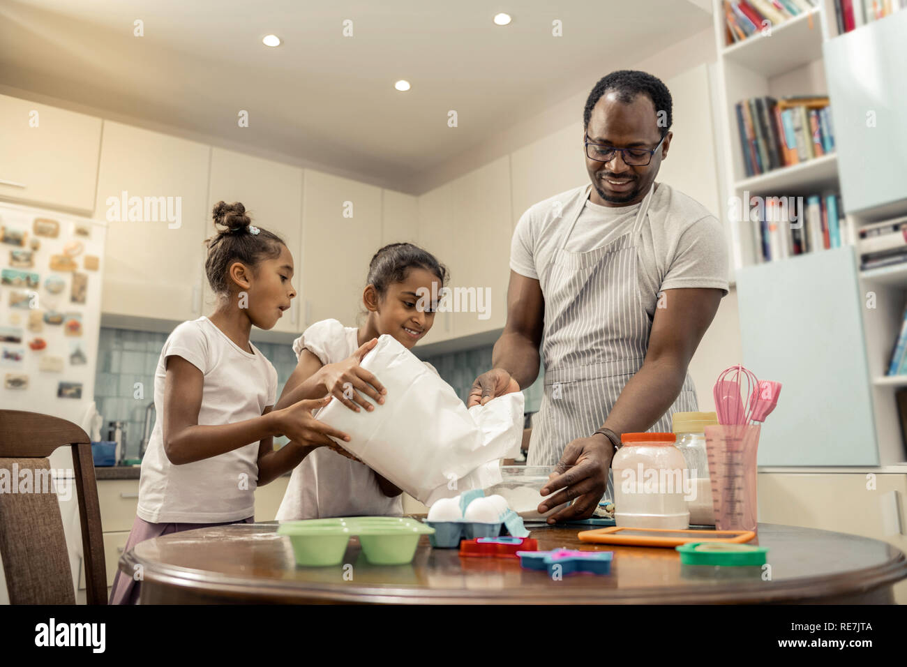 Two little girls feeling excited while cooking with their father Stock ...