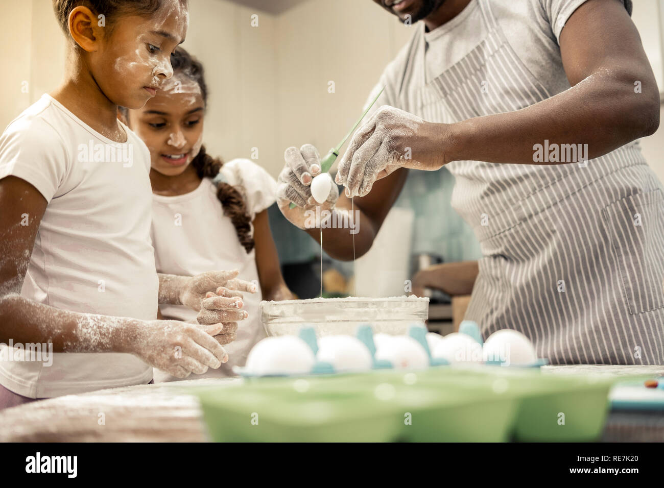 Faces in flour. Funny girls with faces in flour watching their father ...