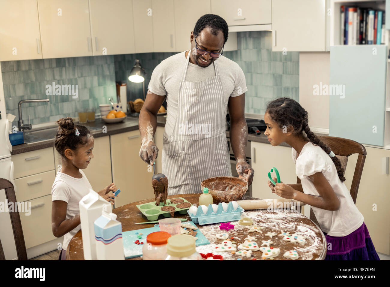 Friendly family laughing while cooking cupcakes together Stock Photo ...