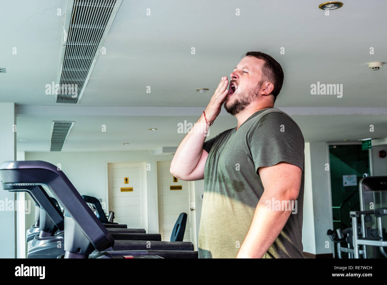 Sweating chubby man walking on running track, warming up on gym ...