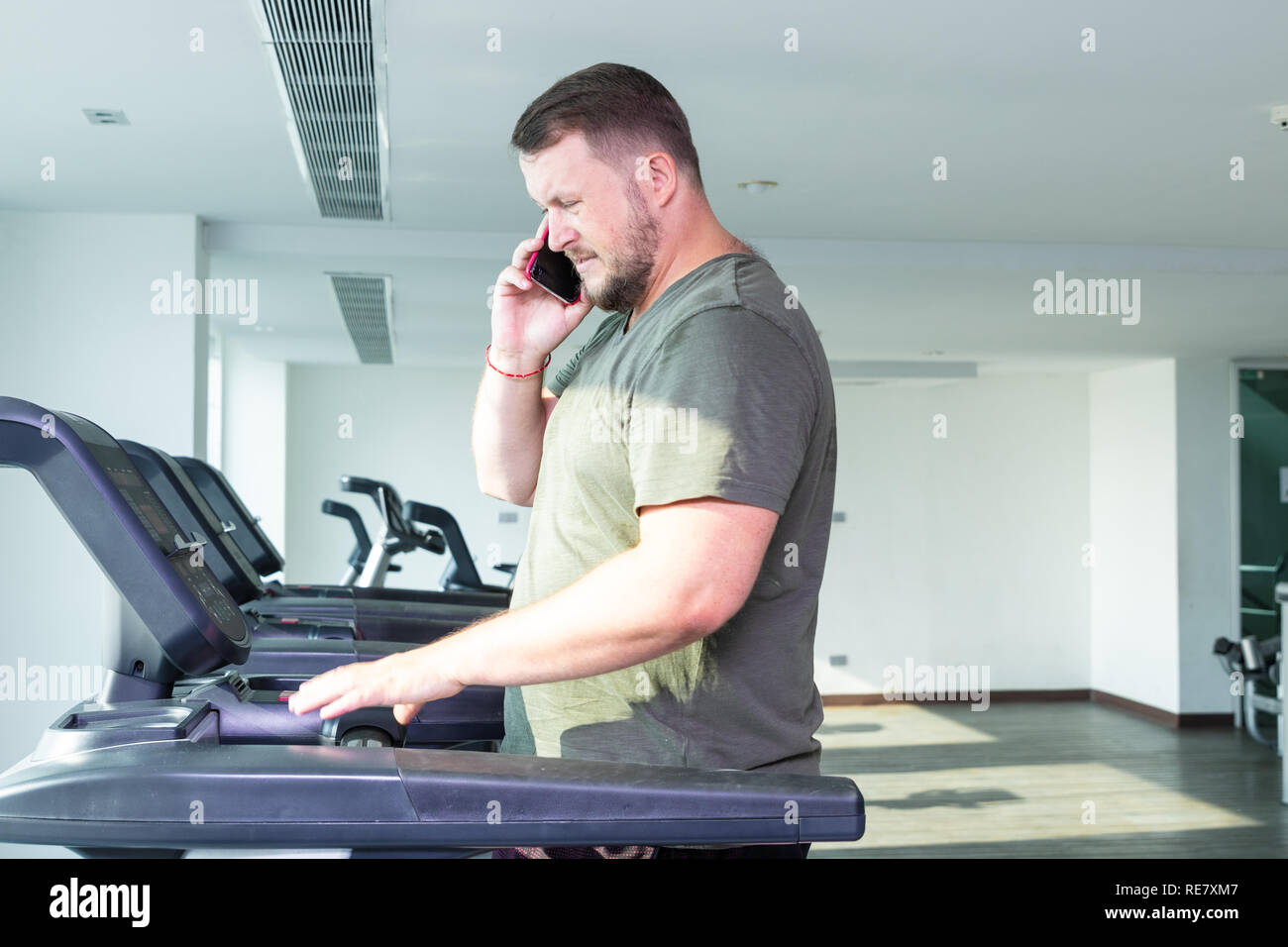 Sweating chubby man walking on running track, warming up on gym ...