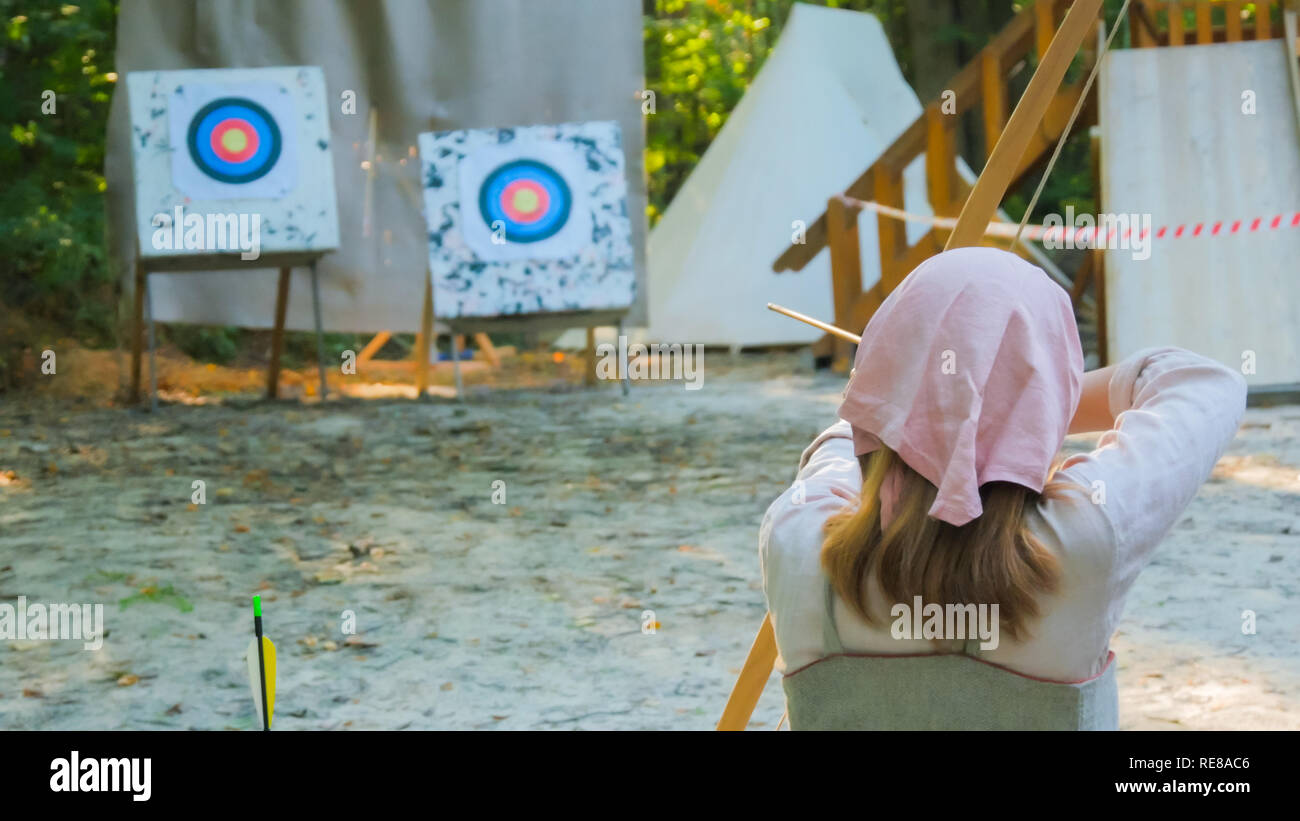 Medieval female archer shooting targets with wooden bow at historical ...