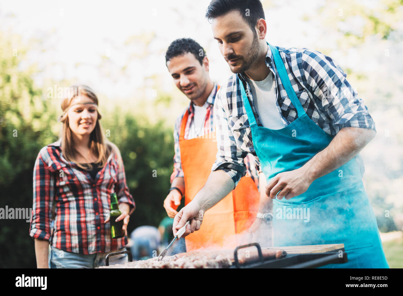 Young people grilling outdoors and smiling happy Stock Photo - Alamy