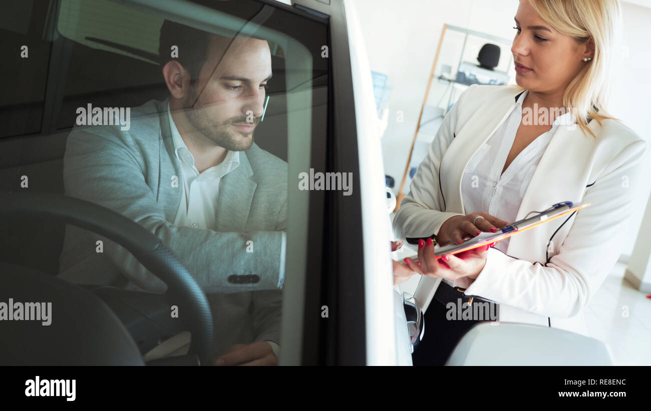 Professional salesperson during work with customer at car dealership ...