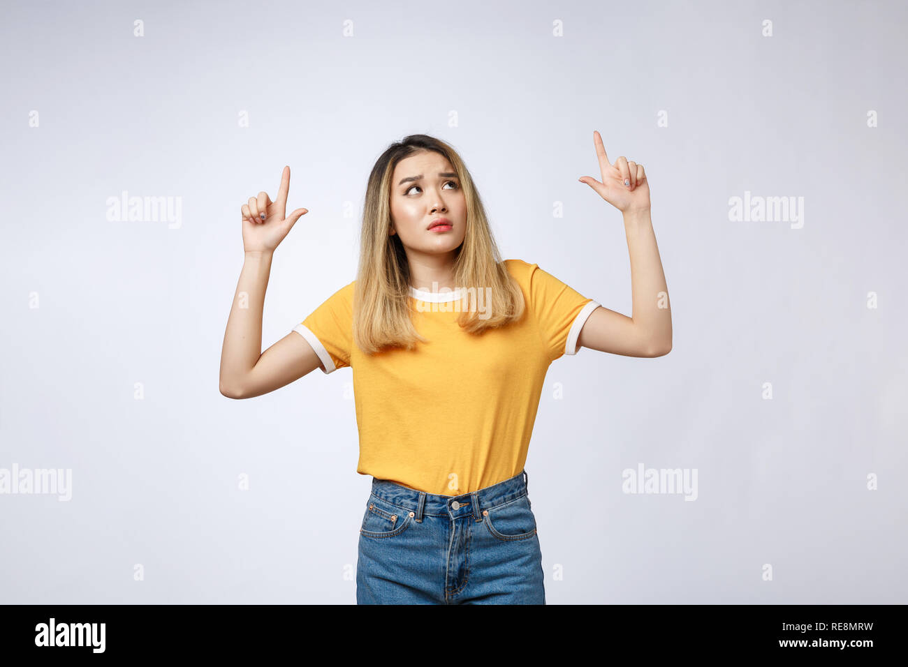 Young Asian woman looking angry and sad while pointing finger at camera ...