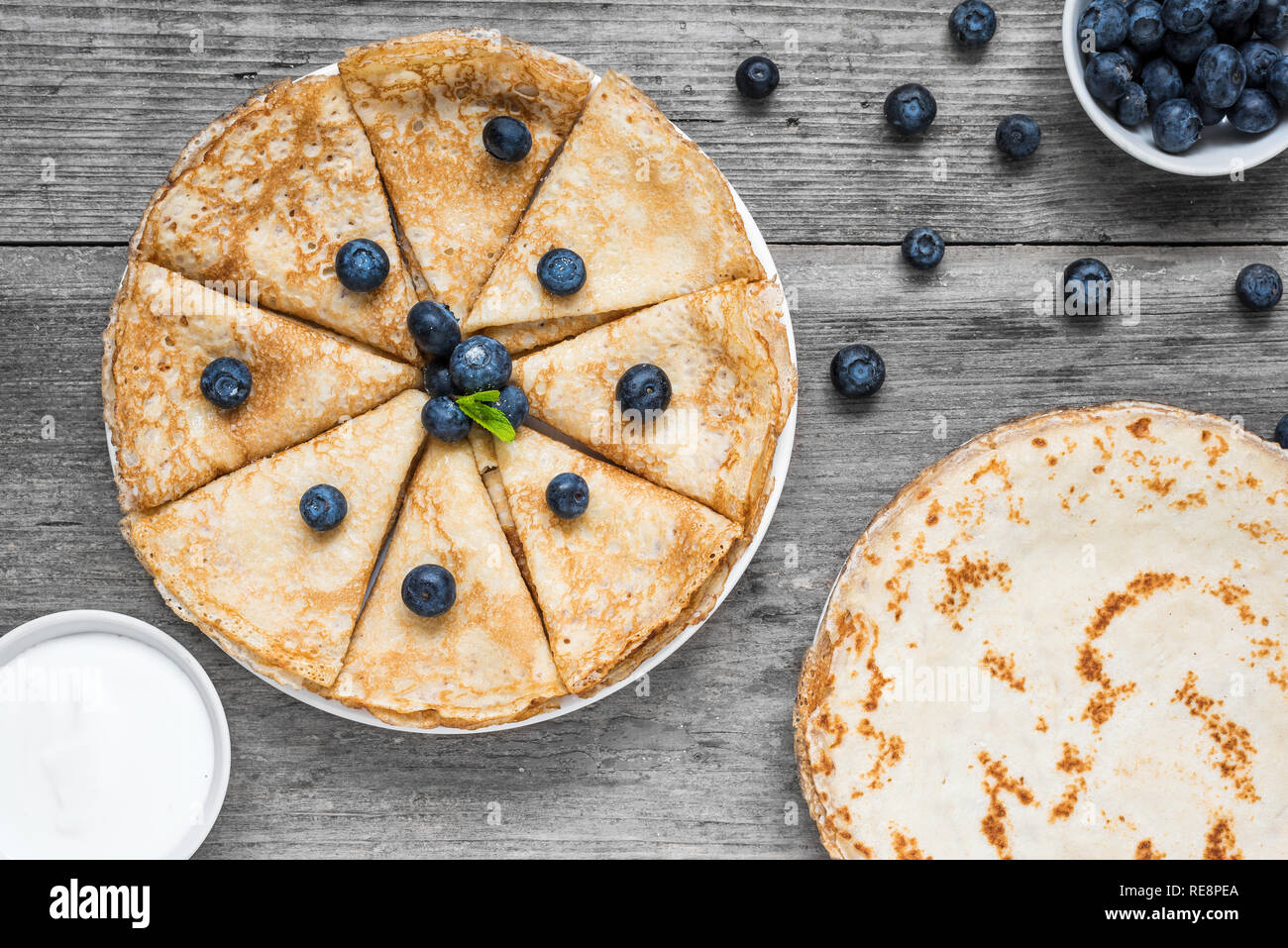 traditional russian pancakes or bliny with blueberries, sour cream and ...