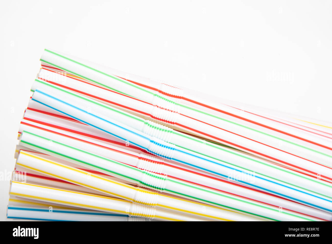 A bunch of single-use white bendy straws with color stripes set on a ...