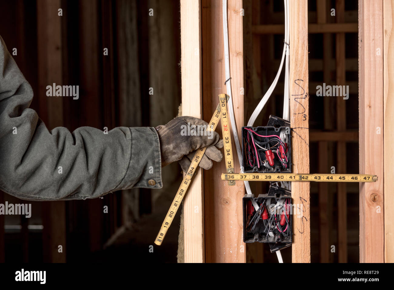 Wall construction shows electrical box that is being measured with a ...