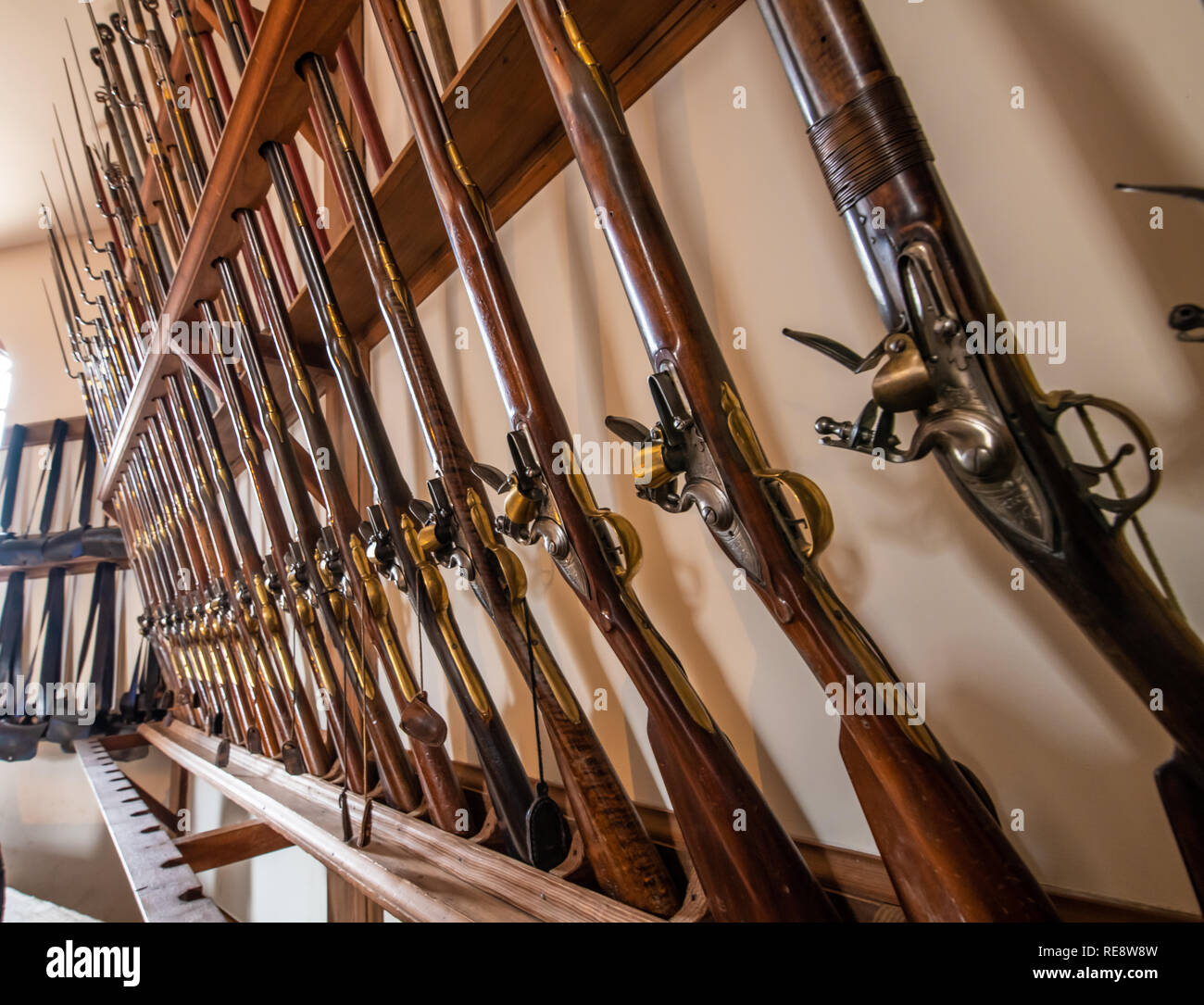 A row of colonial era muskets inside an armory building Stock Photo - Alamy