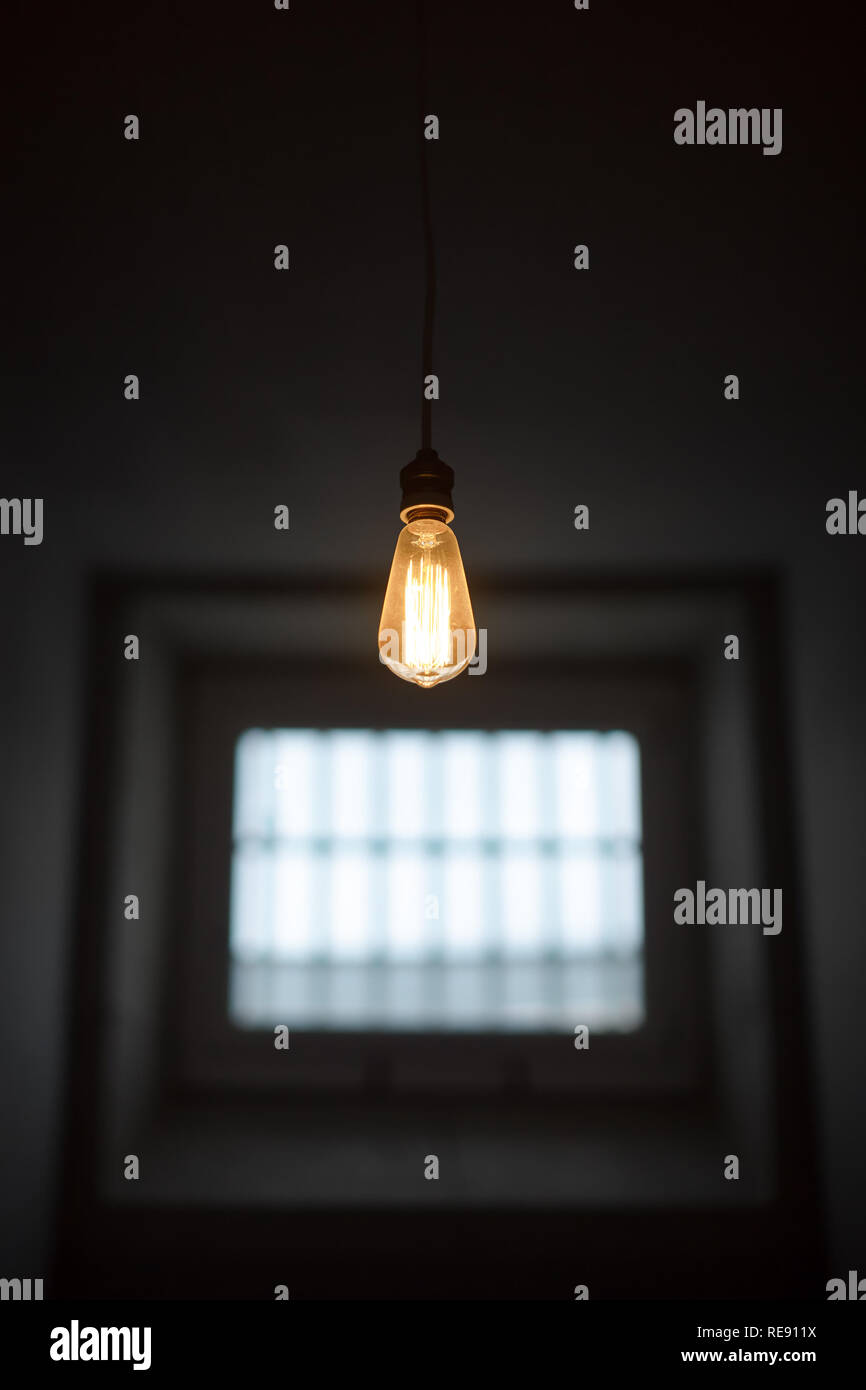Prison cell. Old lamp in ceiling with metal grid on window and sky in ...