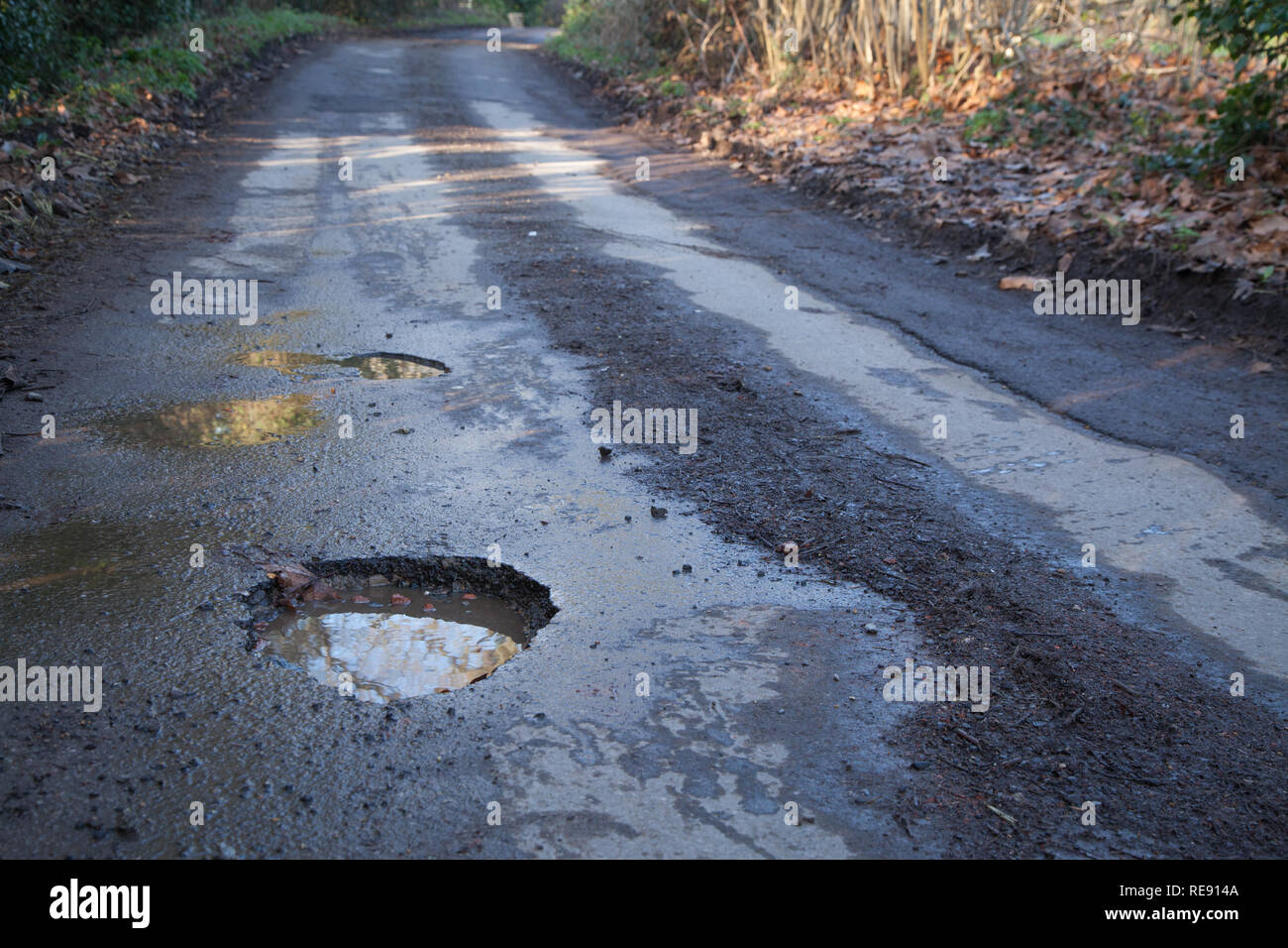 Pothole in country road in English countryside. Asphalt road needing ...