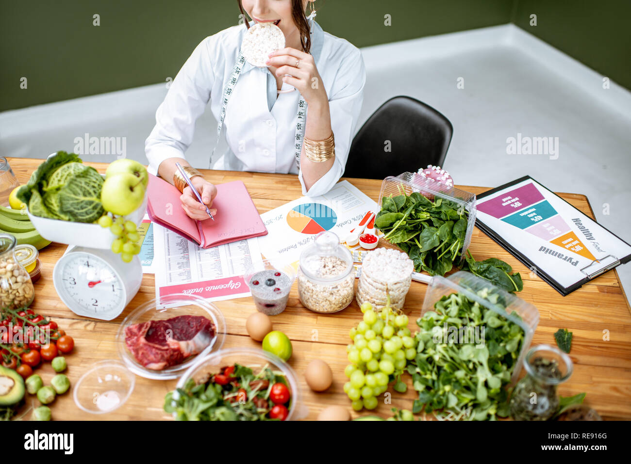 Woman dietitian working on a diet plan sitting with various healthy ...