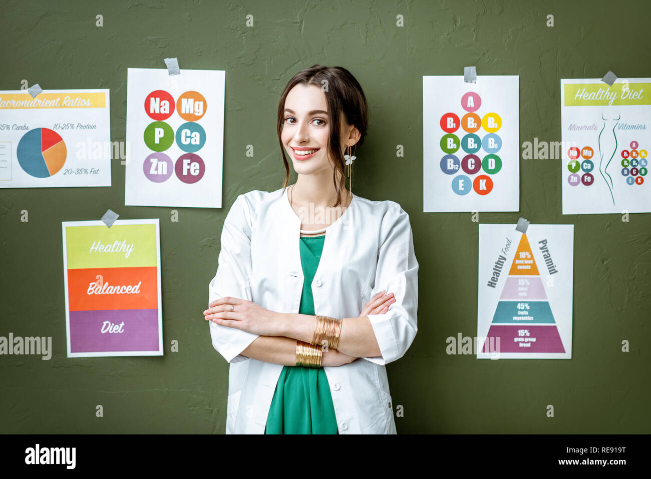 Portrait of a woman dietitian in medical gown standing on the green ...