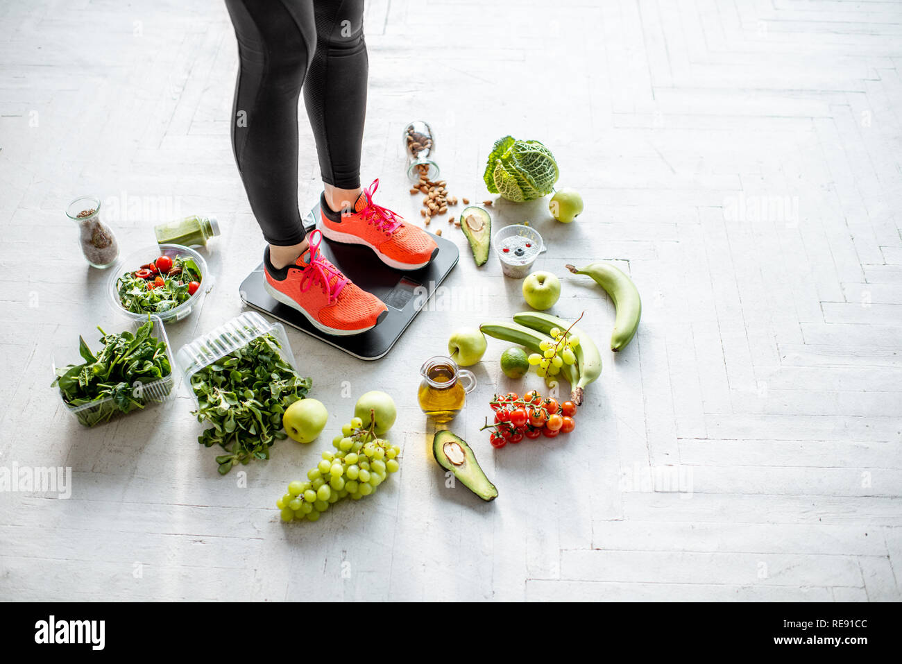 Sports woman weighing on the scales with healthy food around. Weight ...