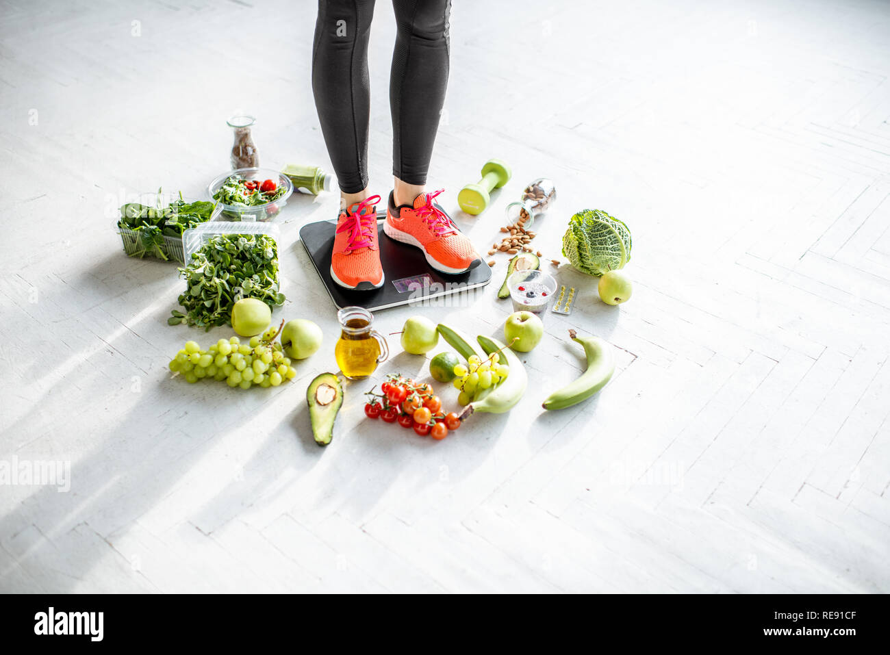 Sports woman weighing on the scales with healthy food around. Weight ...