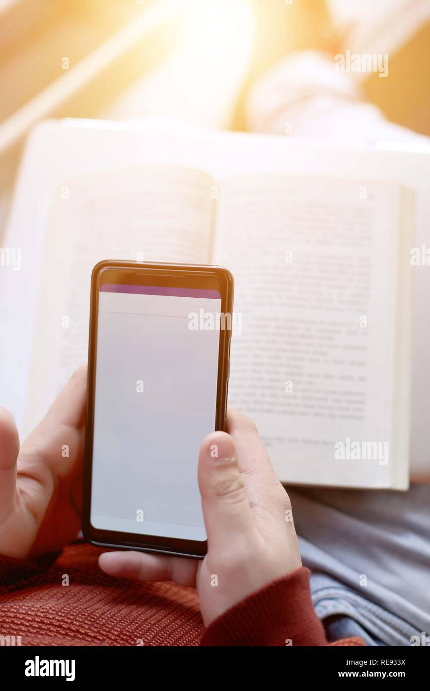 Boy is using phone with open book on the table Stock Photo - Alamy