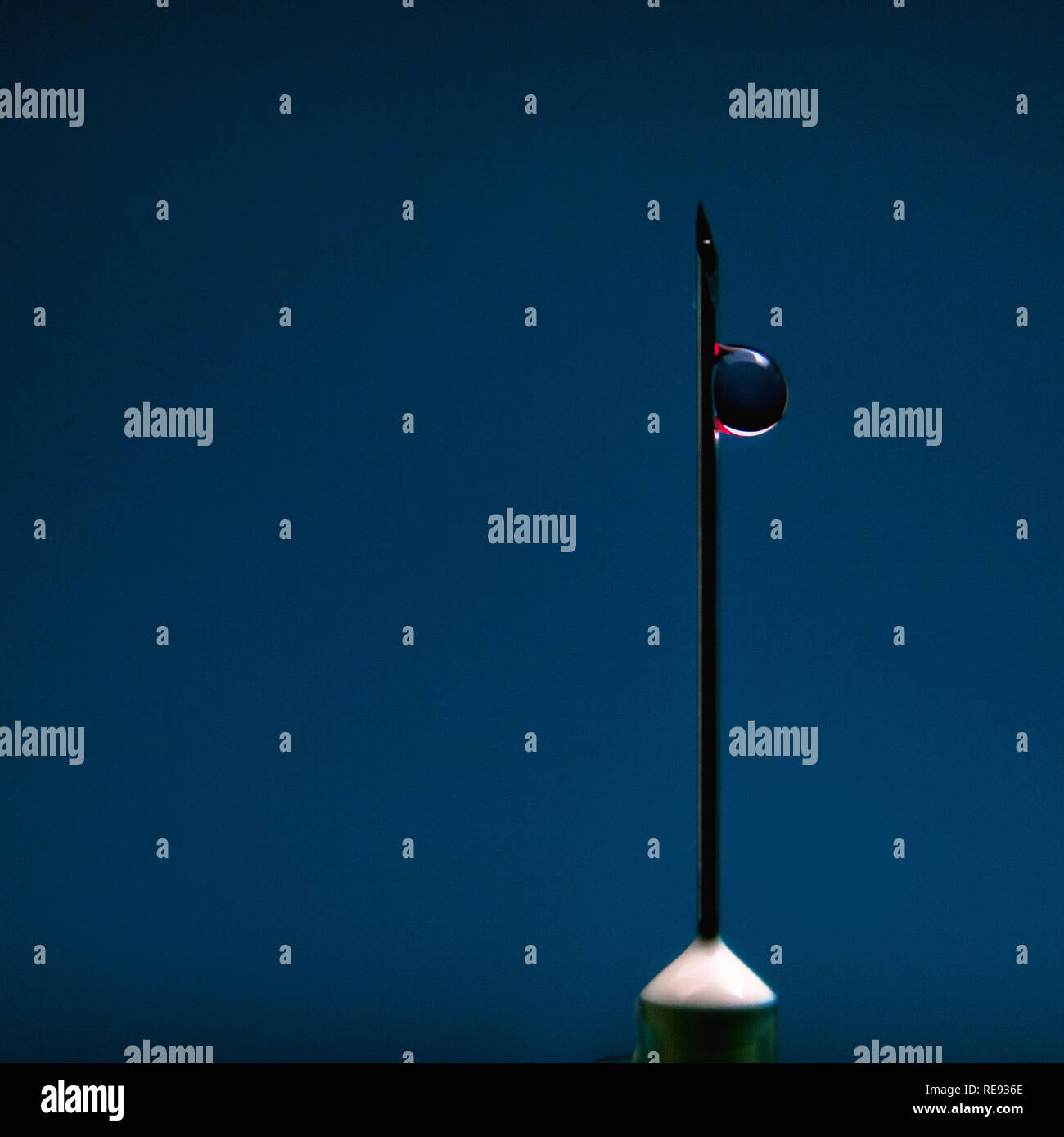 A drop of solution for injection flows down the tip of the needle of a ...