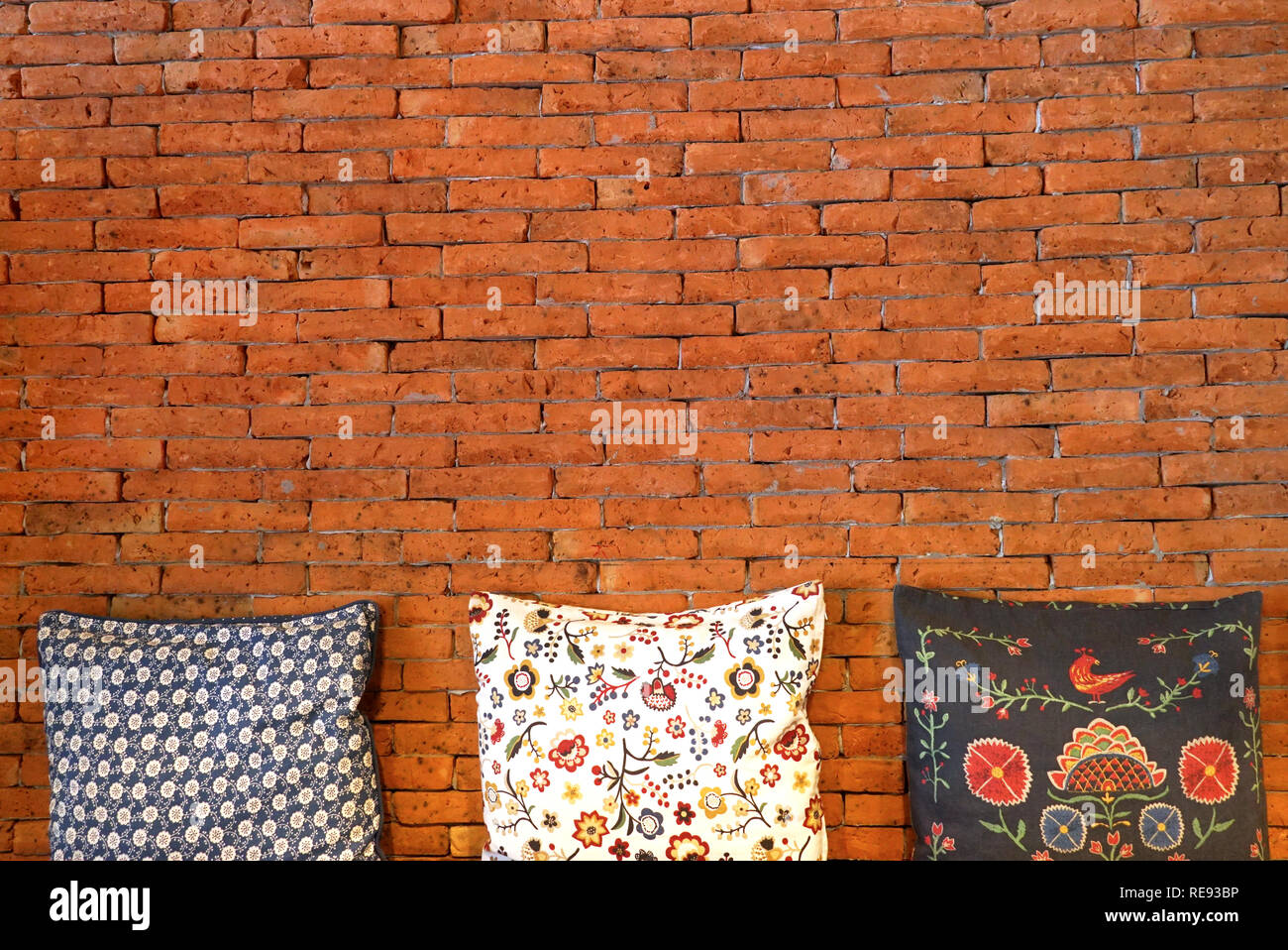 Three pillows with brick wall background Stock Photo - Alamy