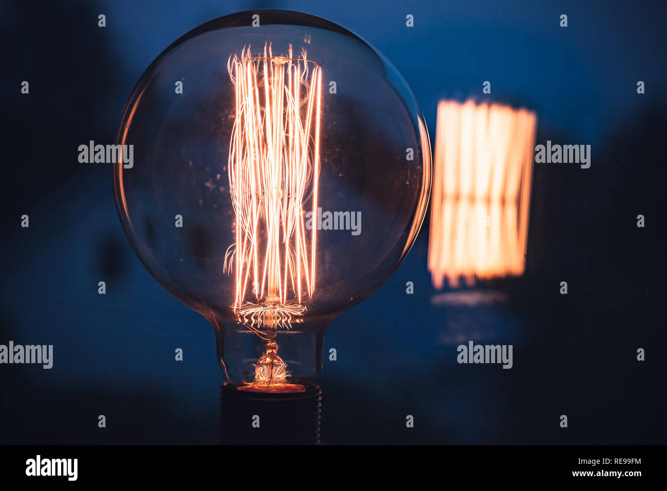 Retro stylized tungsten lamp glowing over dark background, close-up ...