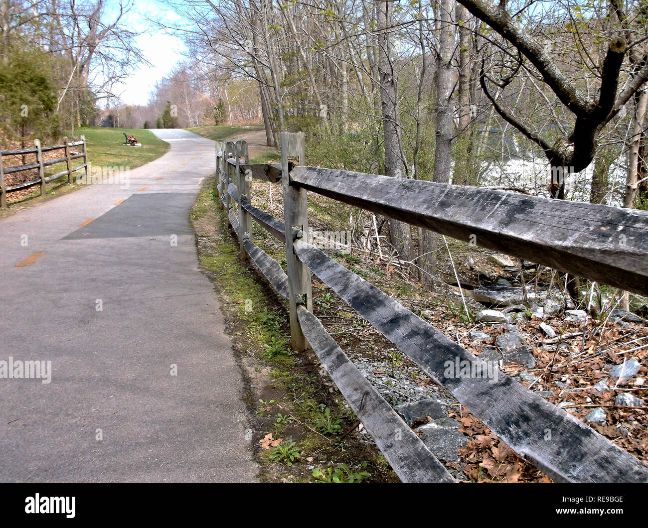 Three rail fence bordering a bike path in a park disappearing into the ...