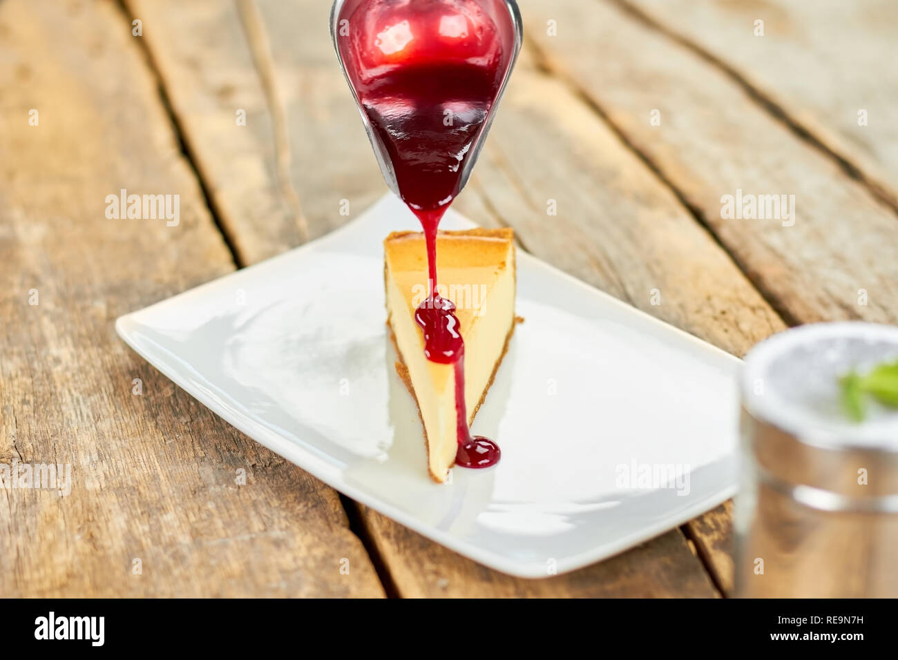 Close up cheesecake pouring with red jam. Pouring jam on cheesecake ...