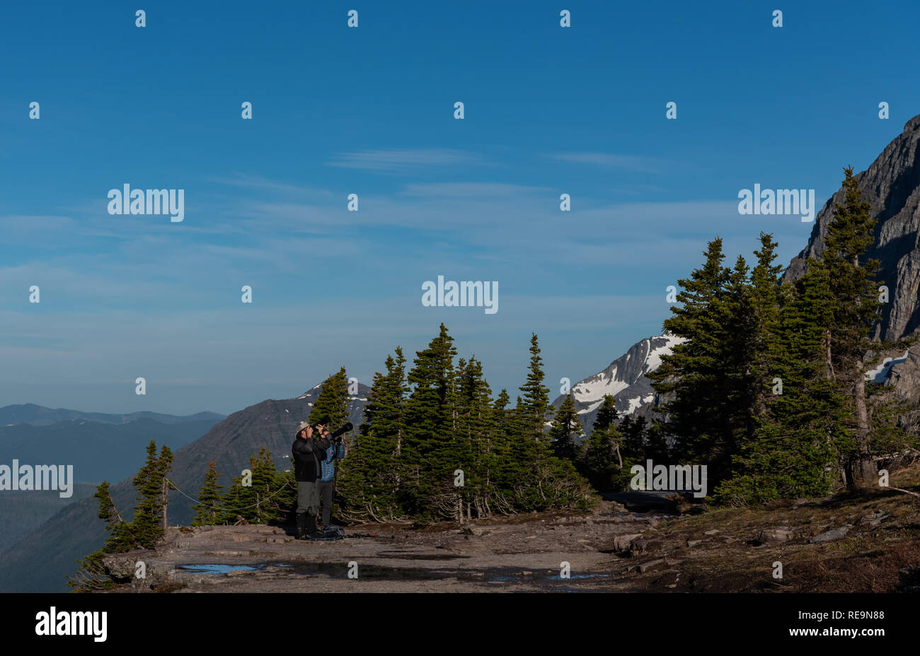 Two Men Photograph Something Above Them from overlook in Glacier' Stock ...