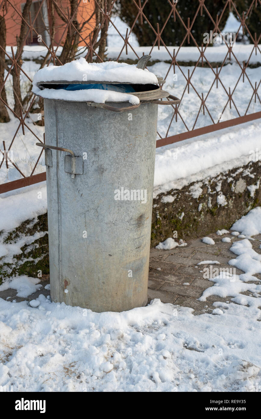 Trash bin at the entrance gate. Metal container covered with snow ...