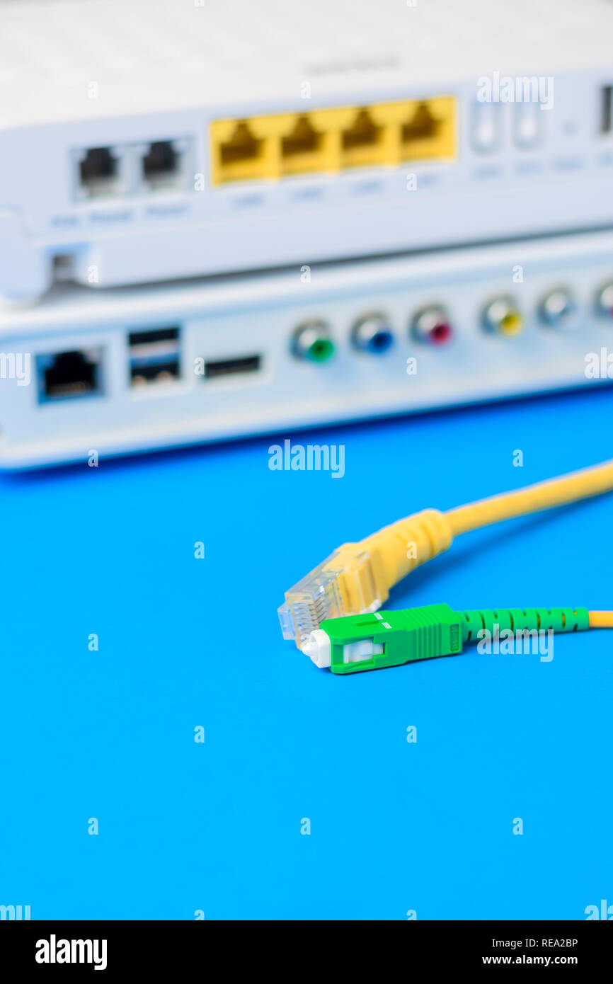 Fiber optical and network cables with internet wireless router on blue ...
