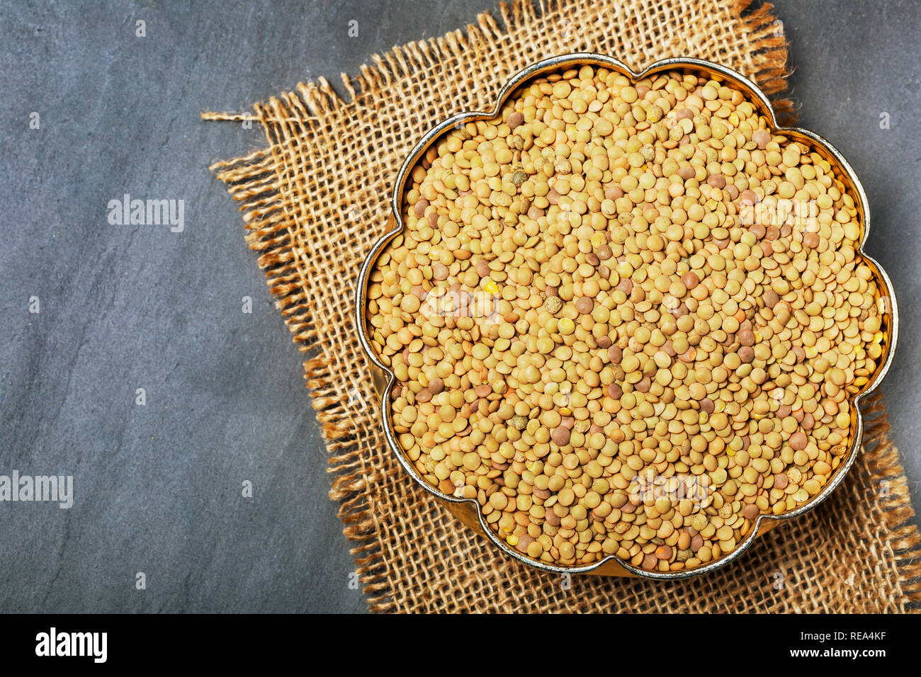 Raw lentils in a golden copper bowl on balck stone background. Healthy ...