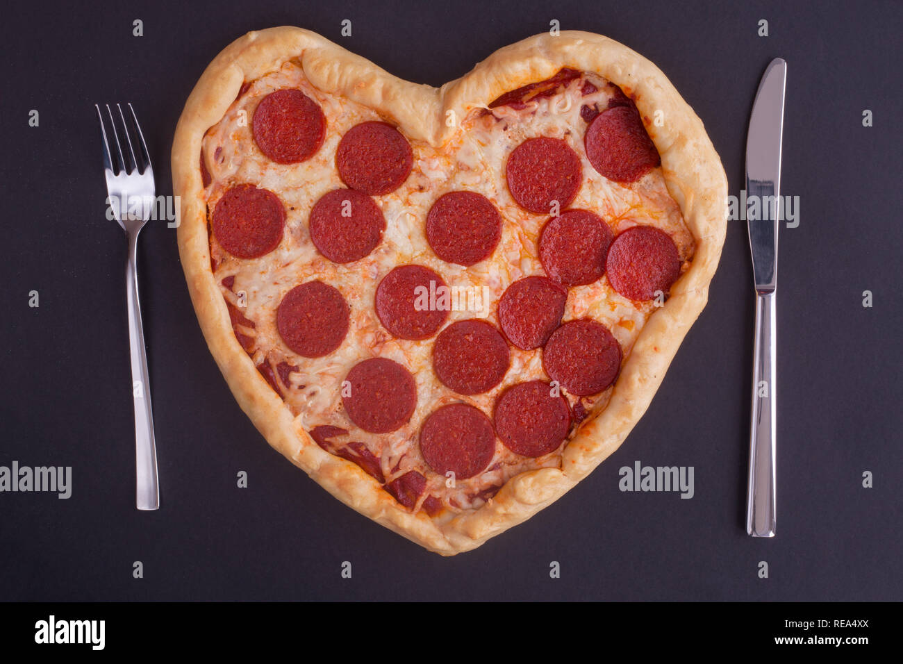 Pizza heart shaped with pepperoni on black background. Concept of ...