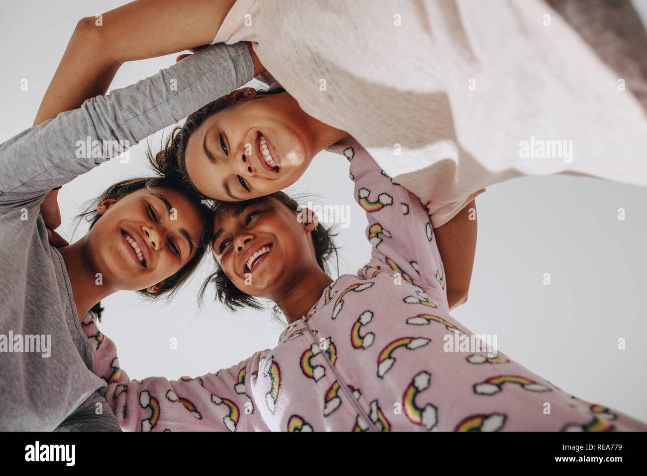 Low angle shot of three girls holding each other in a huddle having fun ...