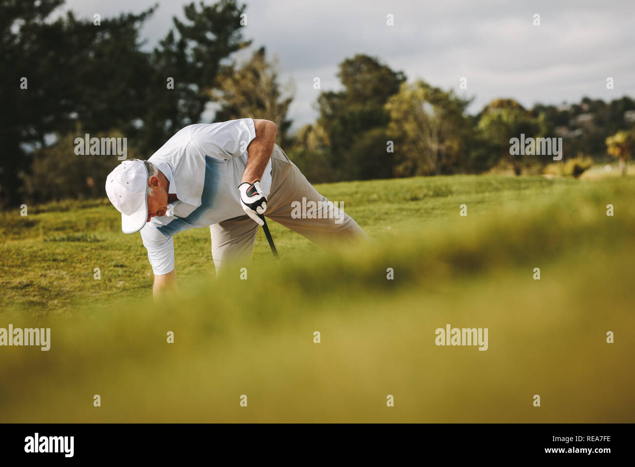 Senior golfer placing the ball on the sand bunker for making his shot ...