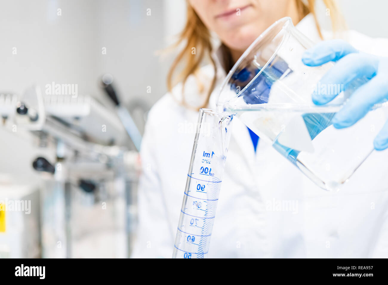 Close up of human hands holding glass recipients with liquid in chemist ...